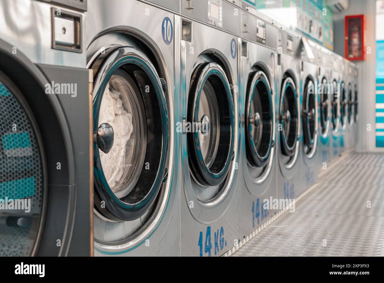 Row of washing machines in public laundry. Commercial cleaning services ...