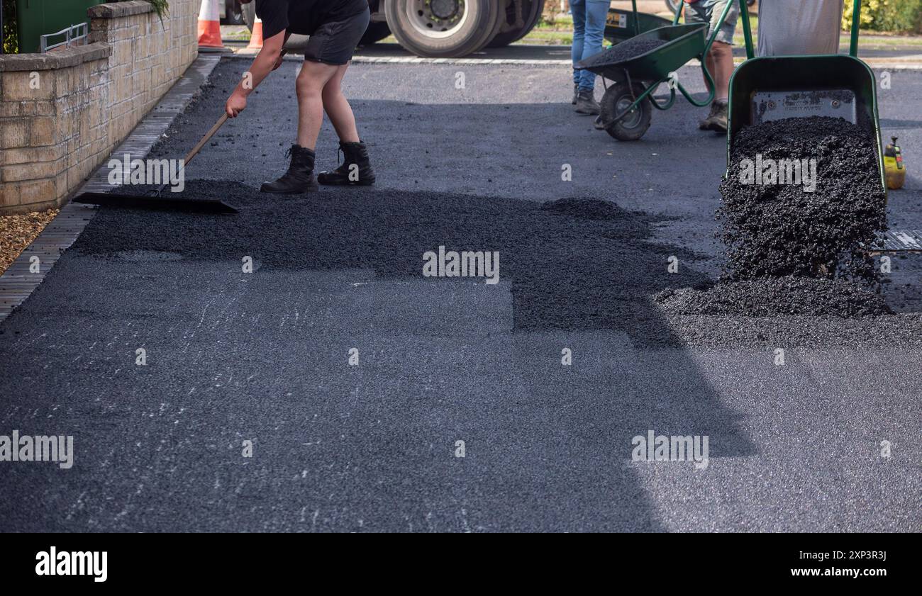 Workers repaving a residential driveway with fresh asphalt using ...
