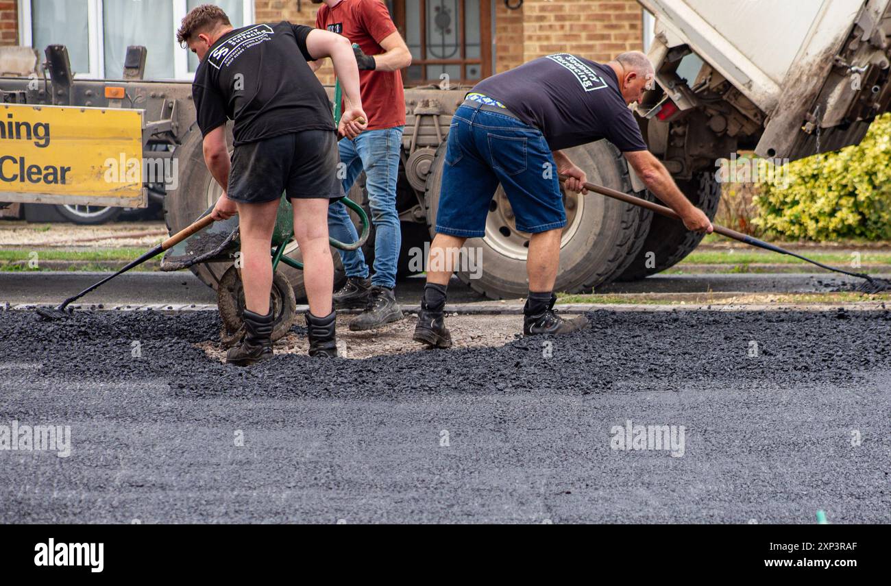 Workers laying fresh asphalt on a road construction site, smoothing out ...