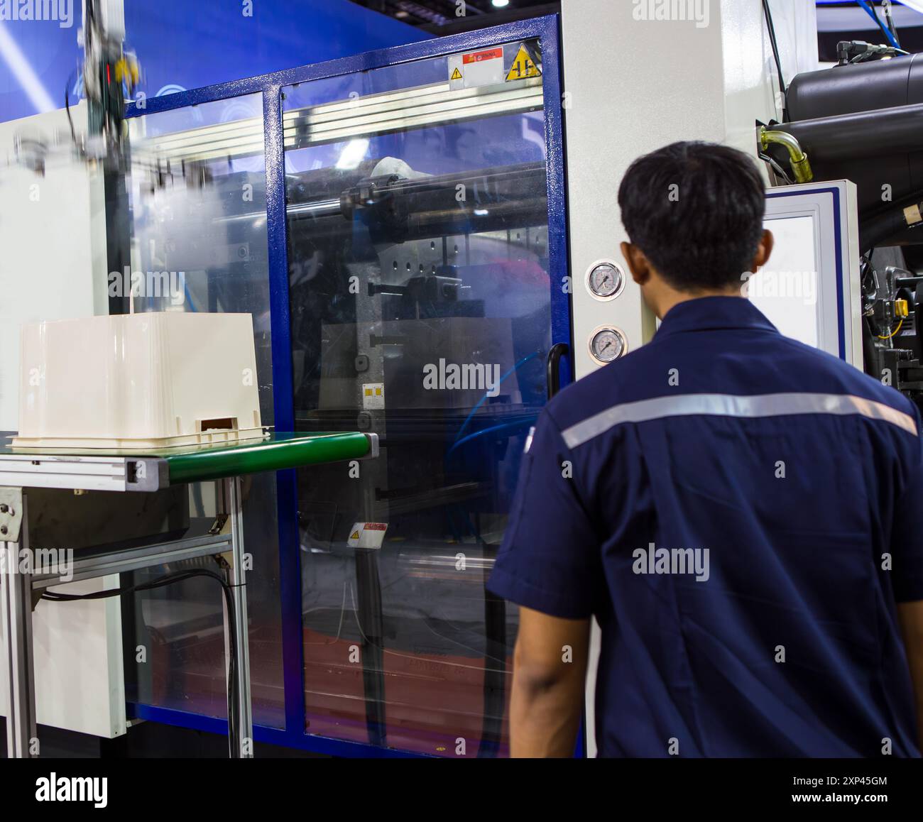 Industrial technician operates injection molding press machine ...