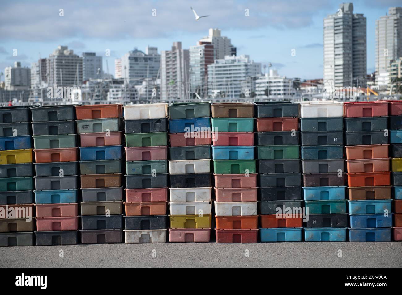 Colorful containers stacked with city skyline under partly cloudy sky ...