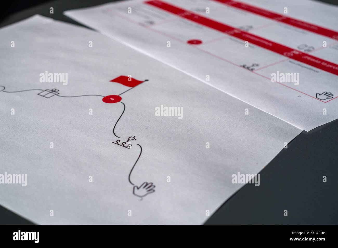 Printed documents with black and red illustrations on dark surface ...