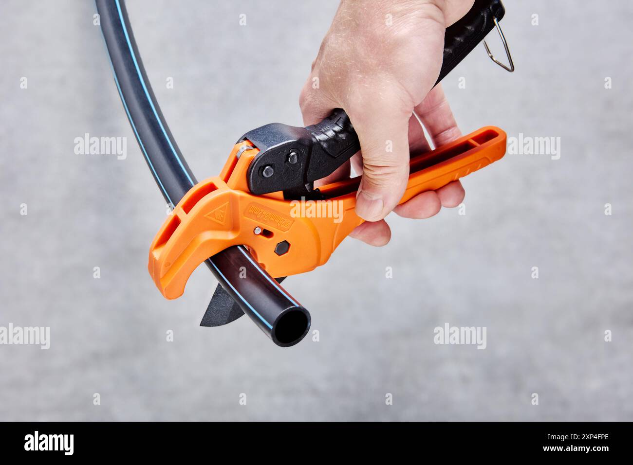 Ratchet pipe cutter is cutting flexible HDPE tube Stock Photo - Alamy