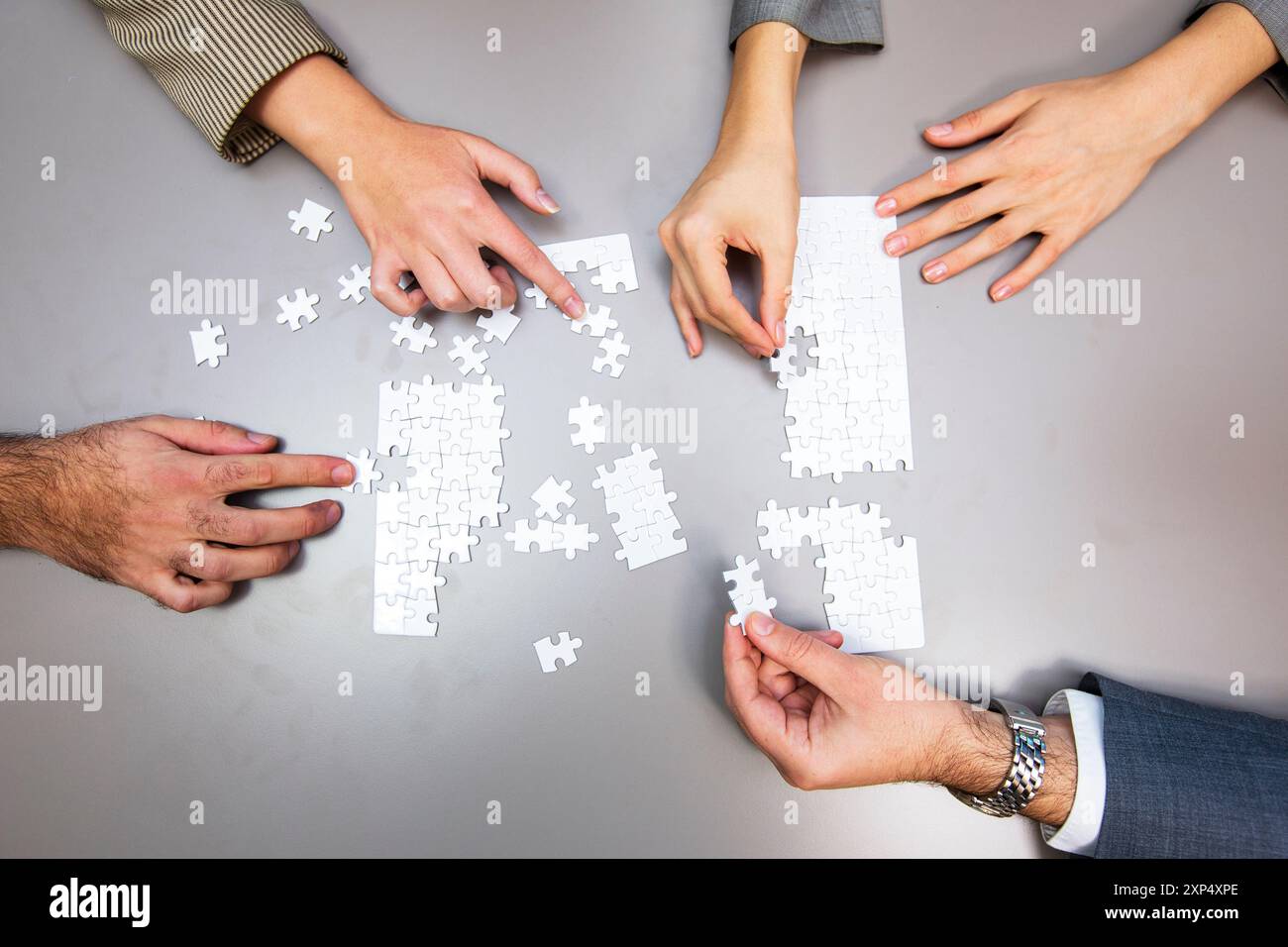 A group of people are working together to solve a jigsaw puzzle Stock ...