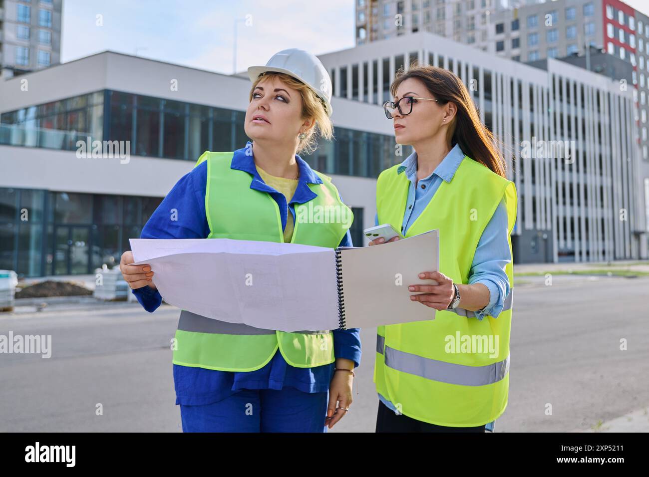 Two confident women talking working on construction of residential ...