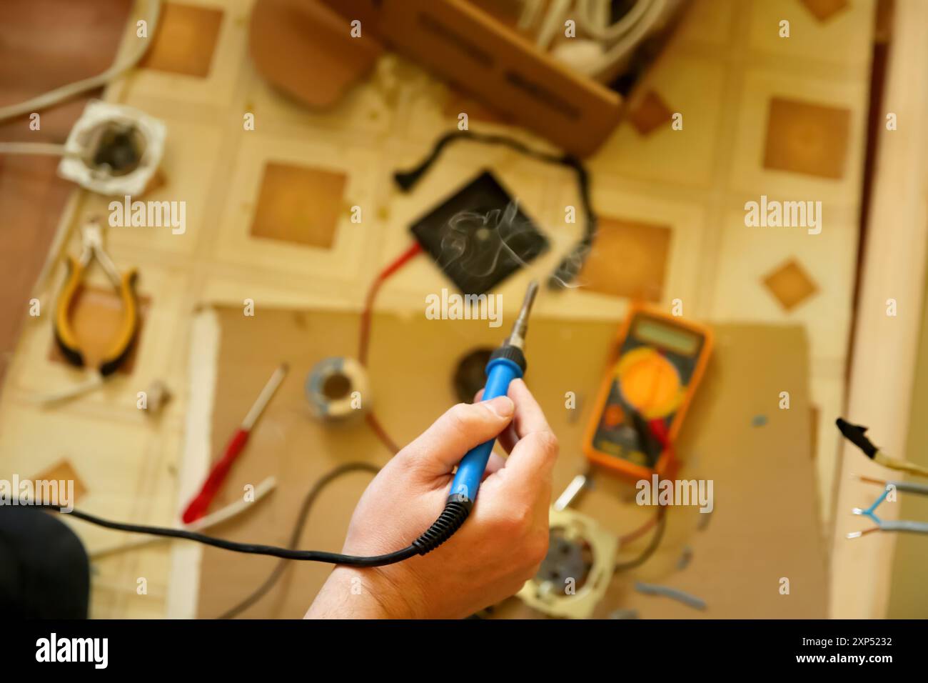 Soldering iron in use, with smoke and wiring on a workbench, top view, ideal for repair ...