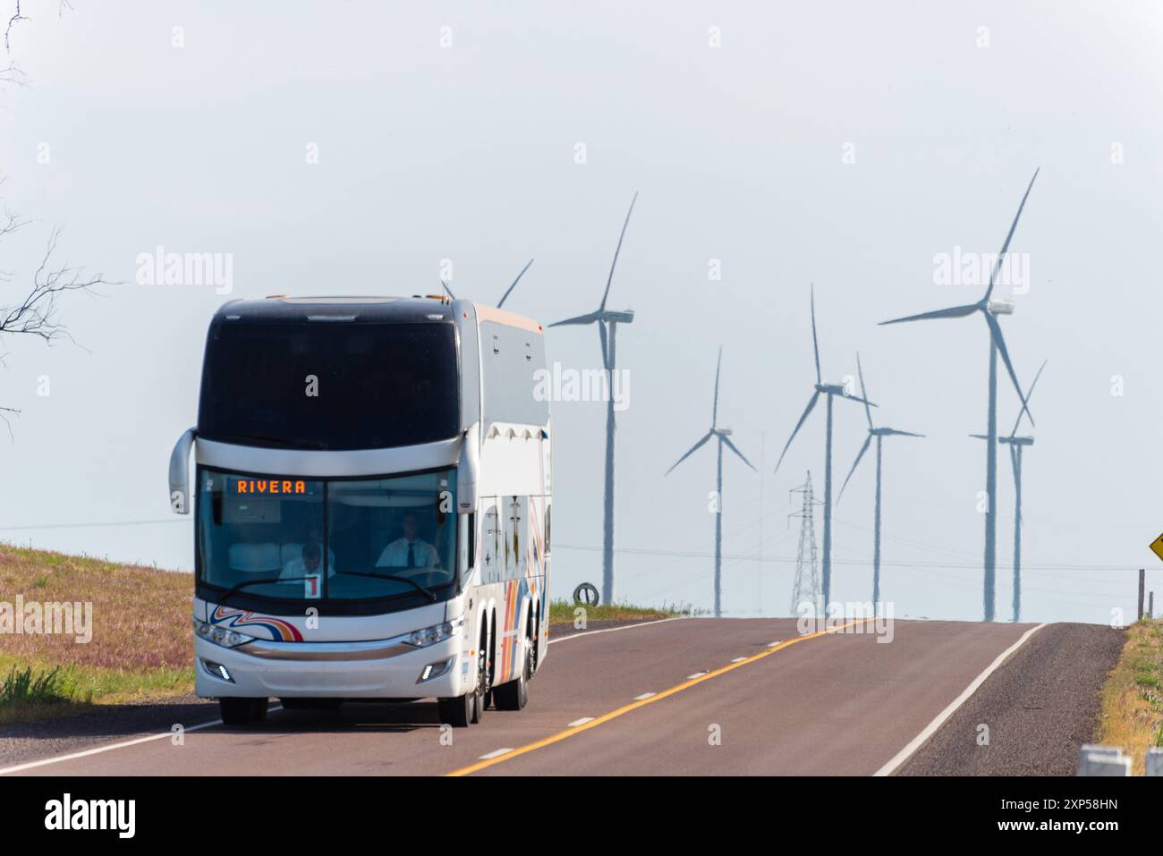 Double-decker bus on rural road with wind turbines showcasing renewable ...