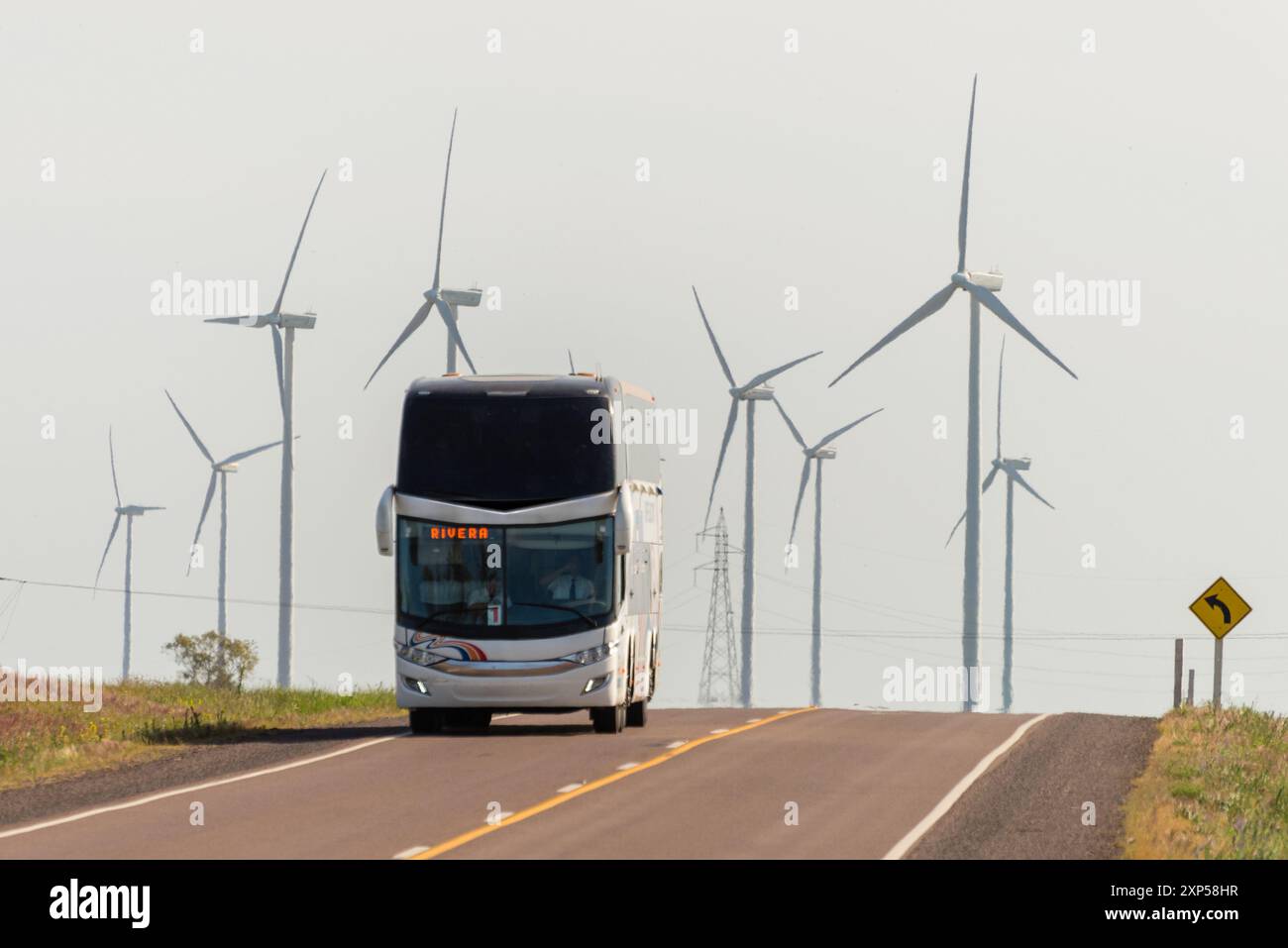 Double-decker bus on rural road with wind turbines in foggy background ...