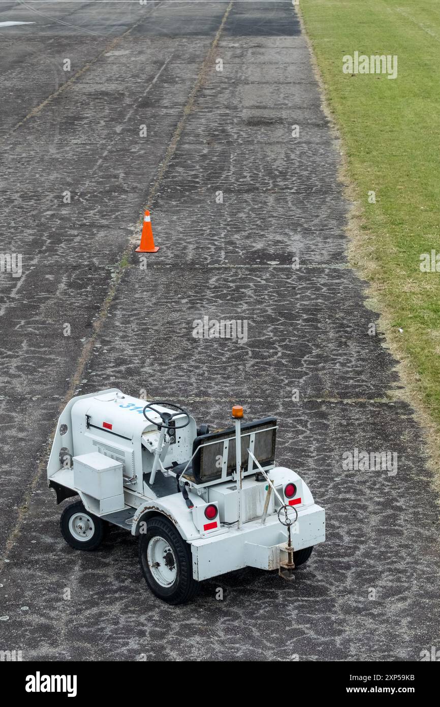 Ground equipment by runway marker on airport service road with lush ...