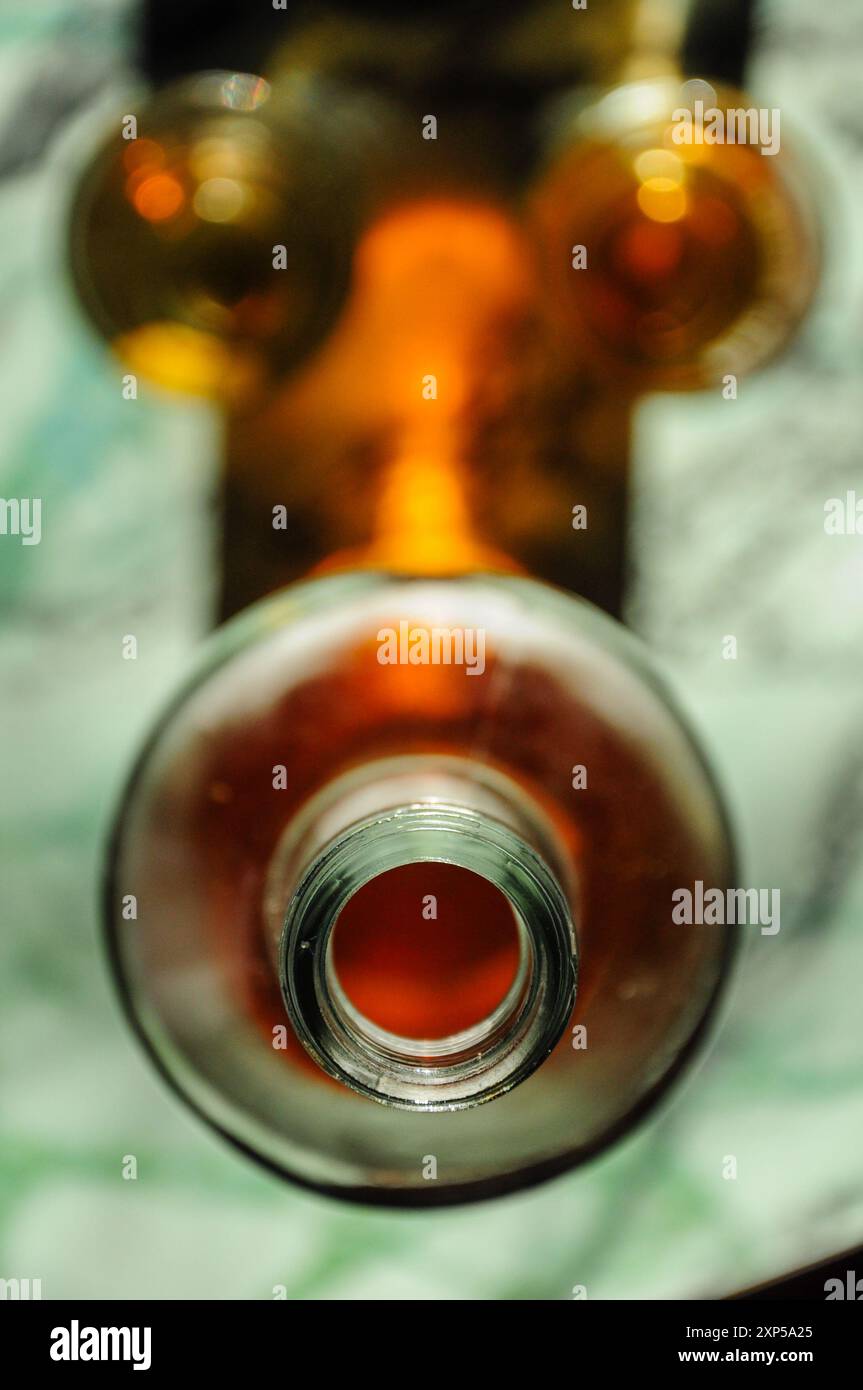 Top-down view of an open bottle with two glasses, filled with amber ...