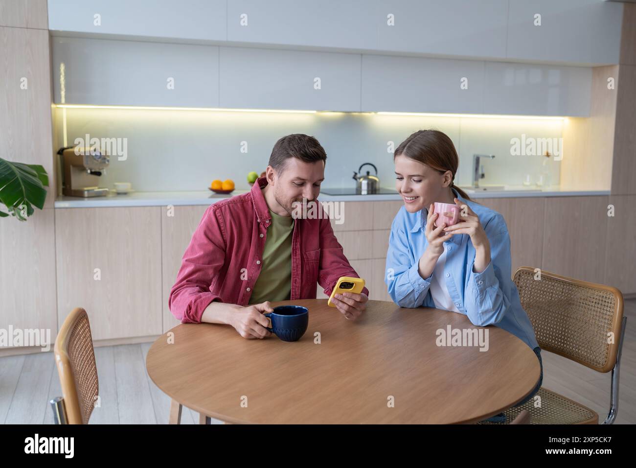 Loving couple spending weekends at home, sitting in kitchen, drinking ...