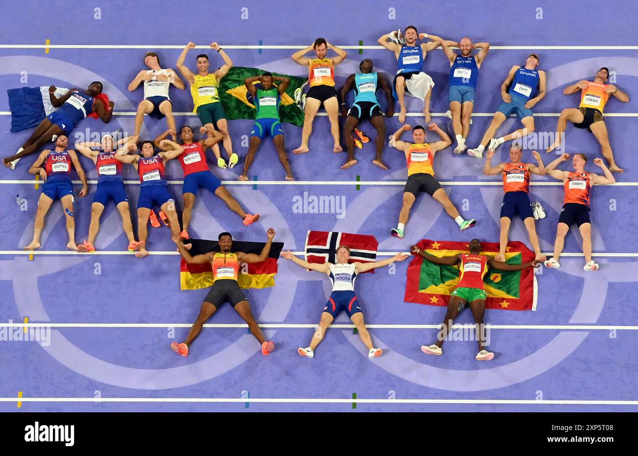 Decathletes lie on a track and pose for cameras after finishing all the ...