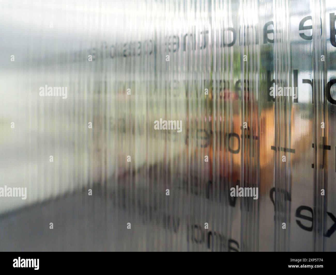 Blurry text written on a textured, translucent surface, with an ...
