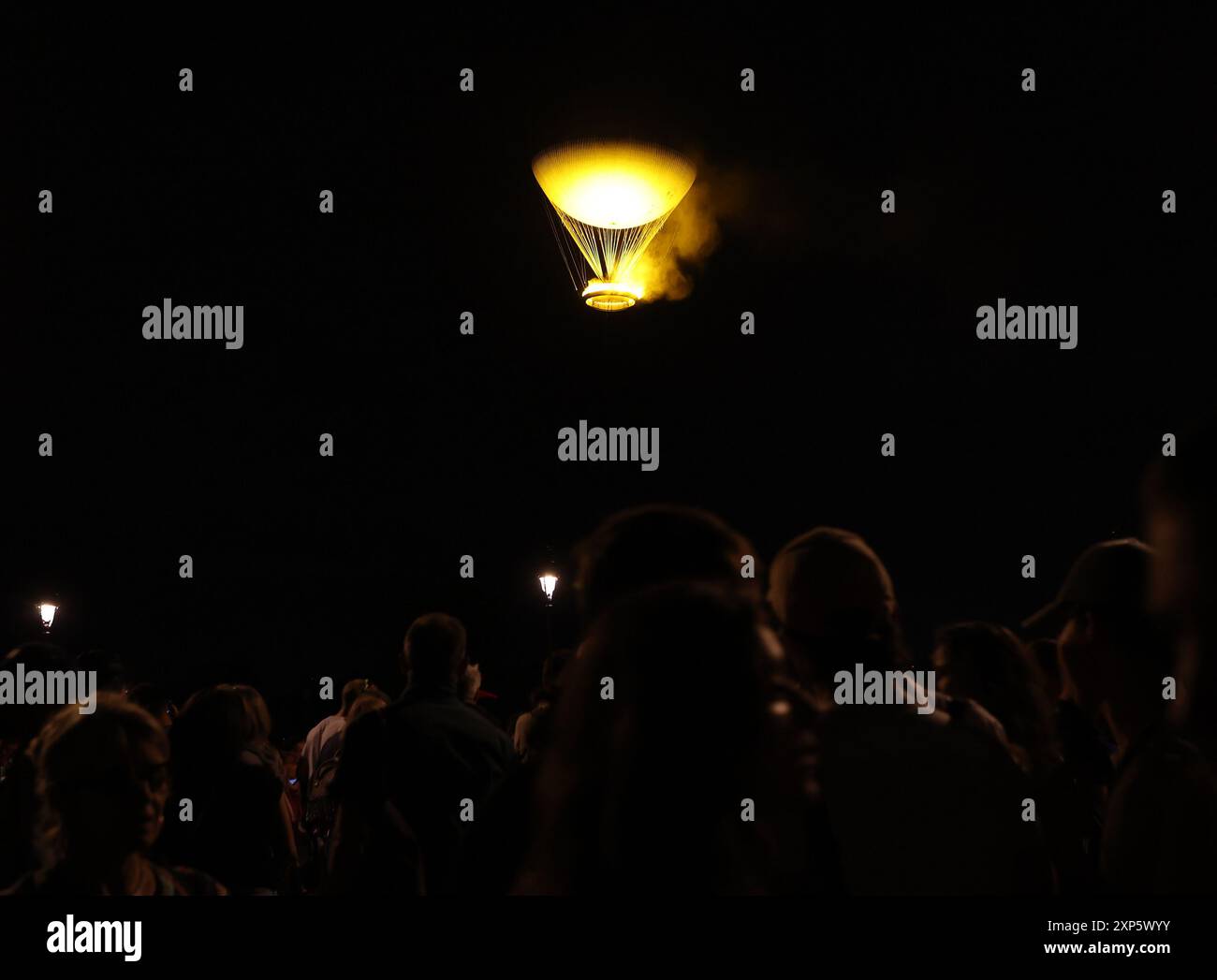 A large golden orb carrying the Olympic Flame flies above the Tulieries ...