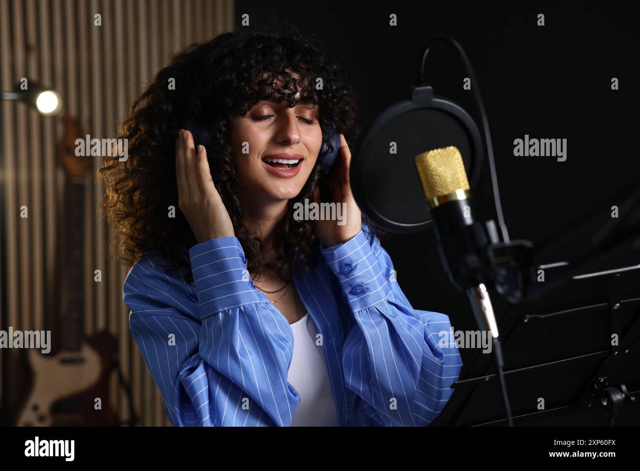 Vocalist with headphones singing into microphone in professional record ...