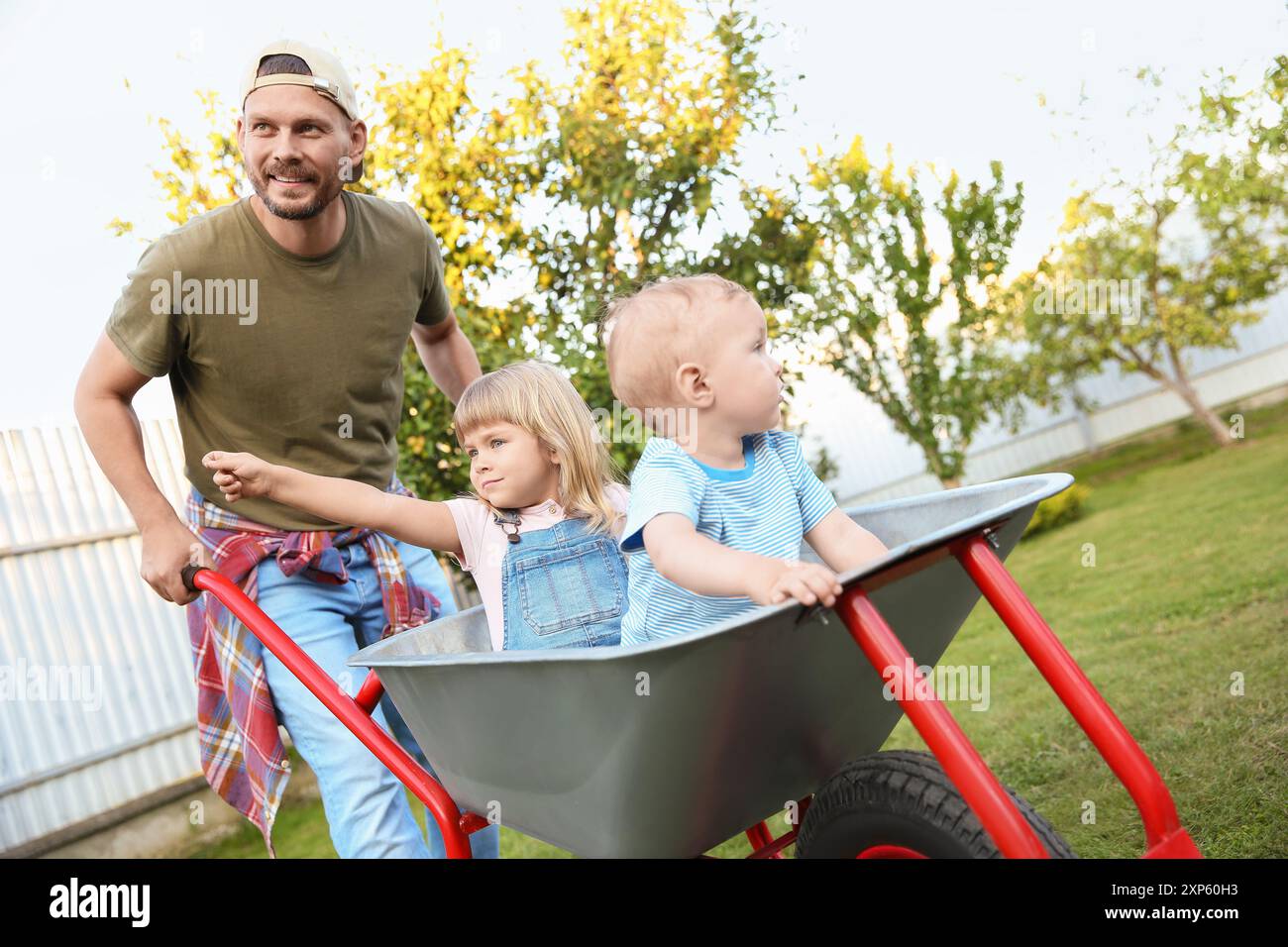 Father pushing wheelbarrow with his kids outdoors Stock Photo - Alamy