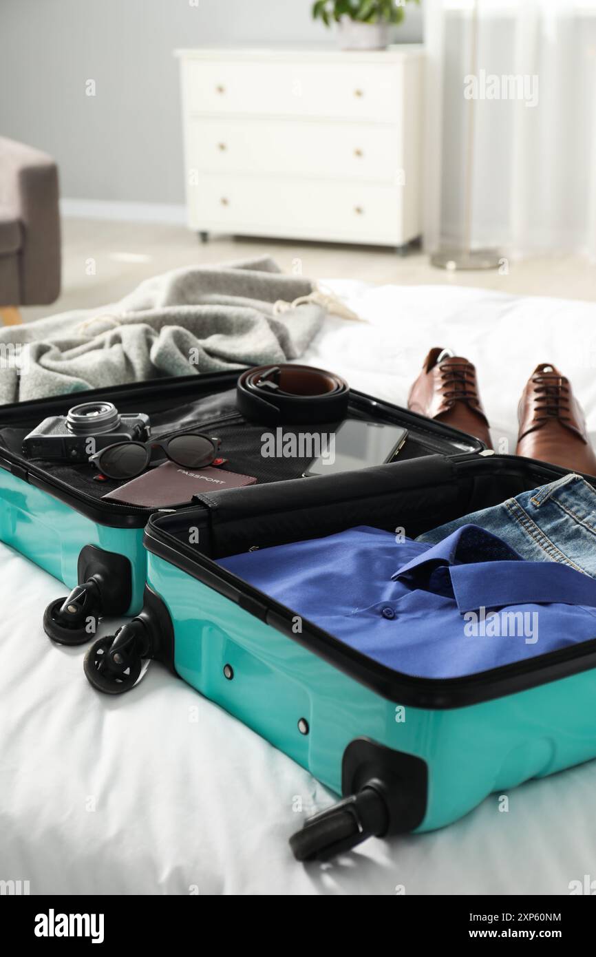 Open suitcase with traveler's belongings on bed Stock Photo - Alamy