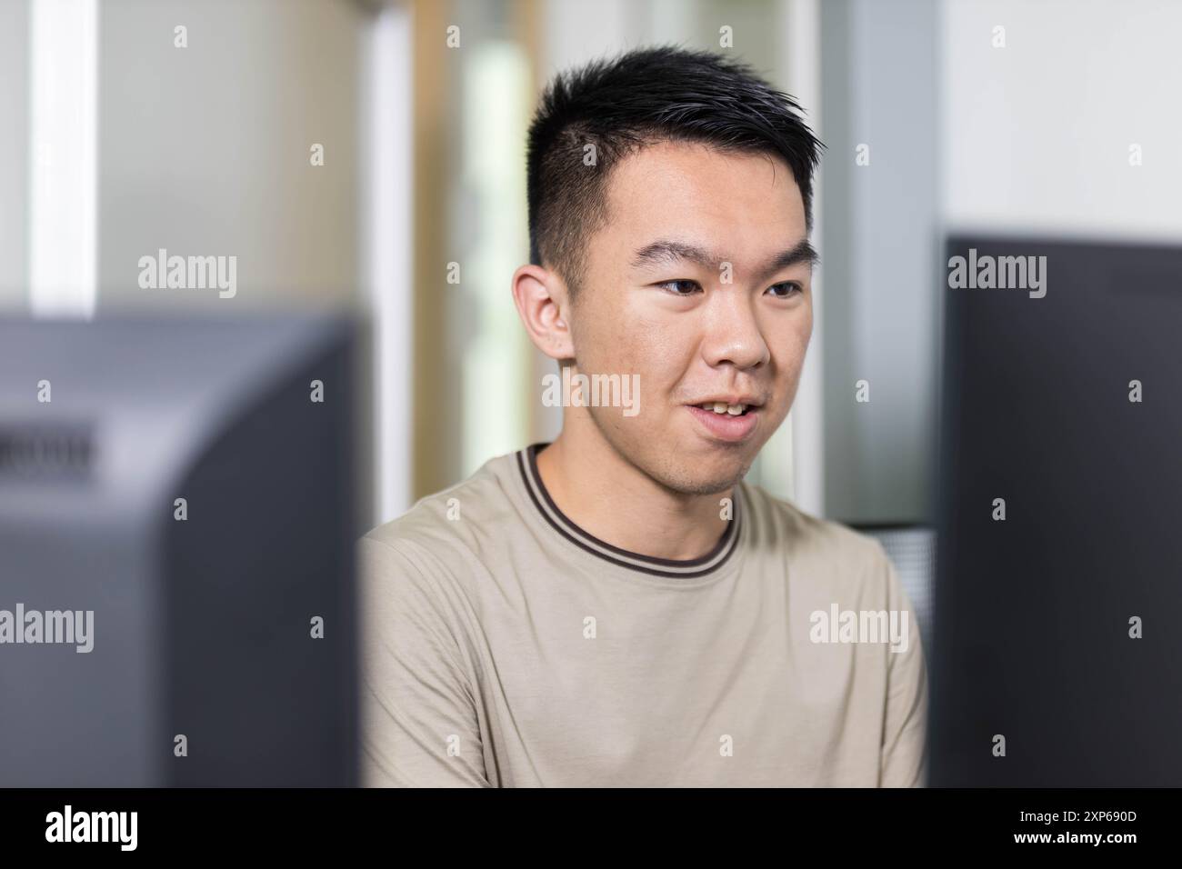 A male college student is currently seated in front of computer ...