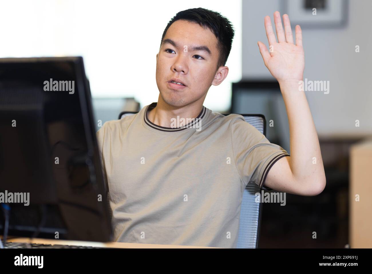 A young Asian teenage student is sitting at a computer in the lab ...