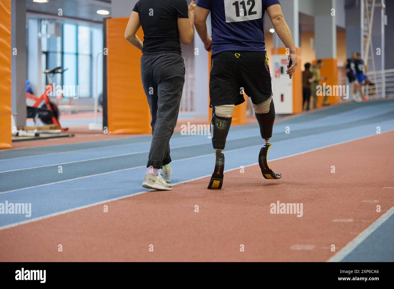 Coach assisting the veteran with double amputation to run on ...