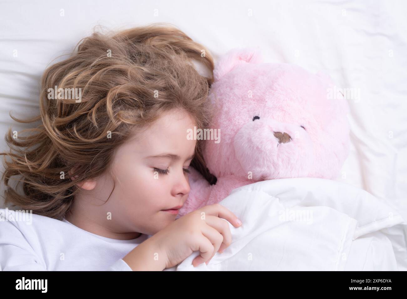 Daily sleeping. Adorable kid sleeps in bed with a toy teddy bear ...