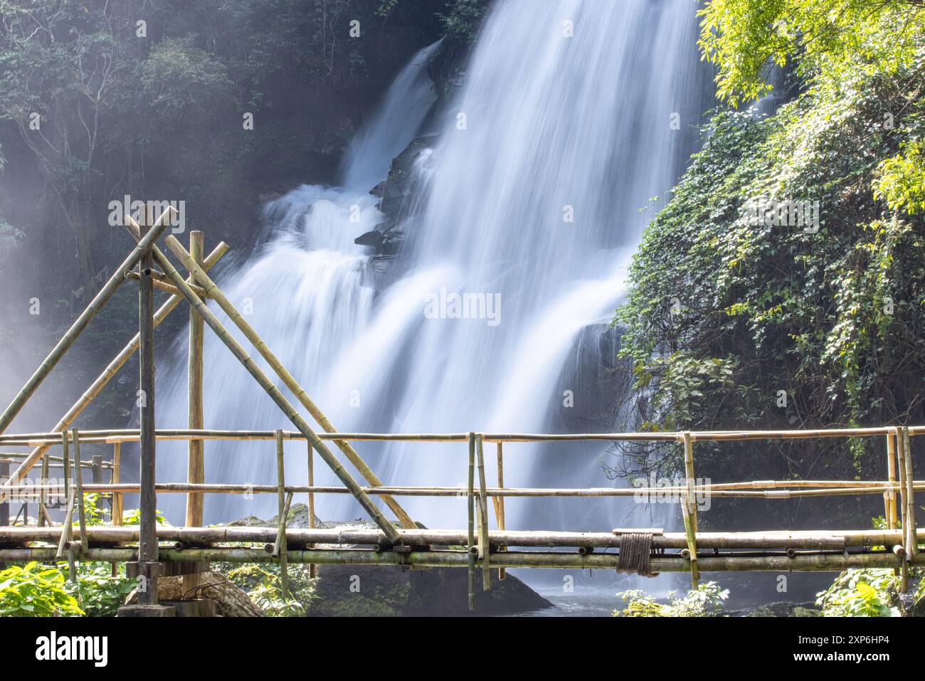The landscape of a bamboo footbridge across a waterfall near a Karen ...