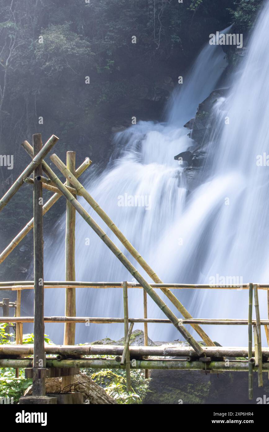 The landscape of a bamboo footbridge across a waterfall near a Karen ...