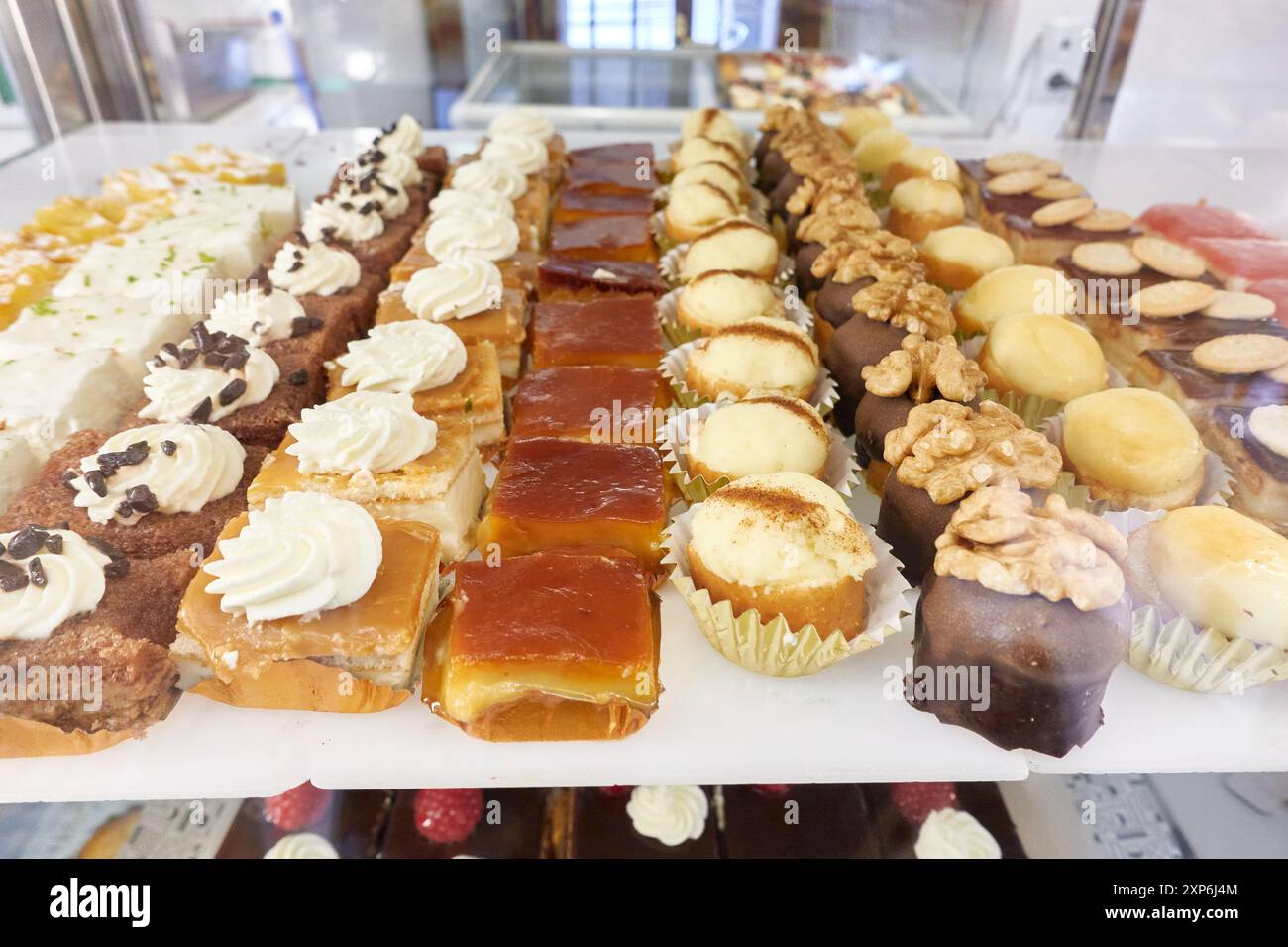 Display of cakes arranged in rows in the window of a bakery: tocinos de ...