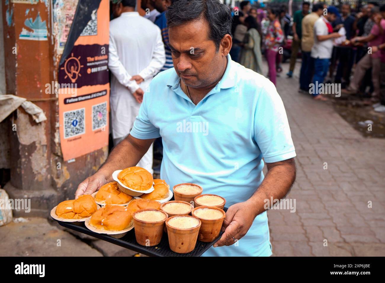 An Indian man carries tea and bread for his friends at a tea stall in ...