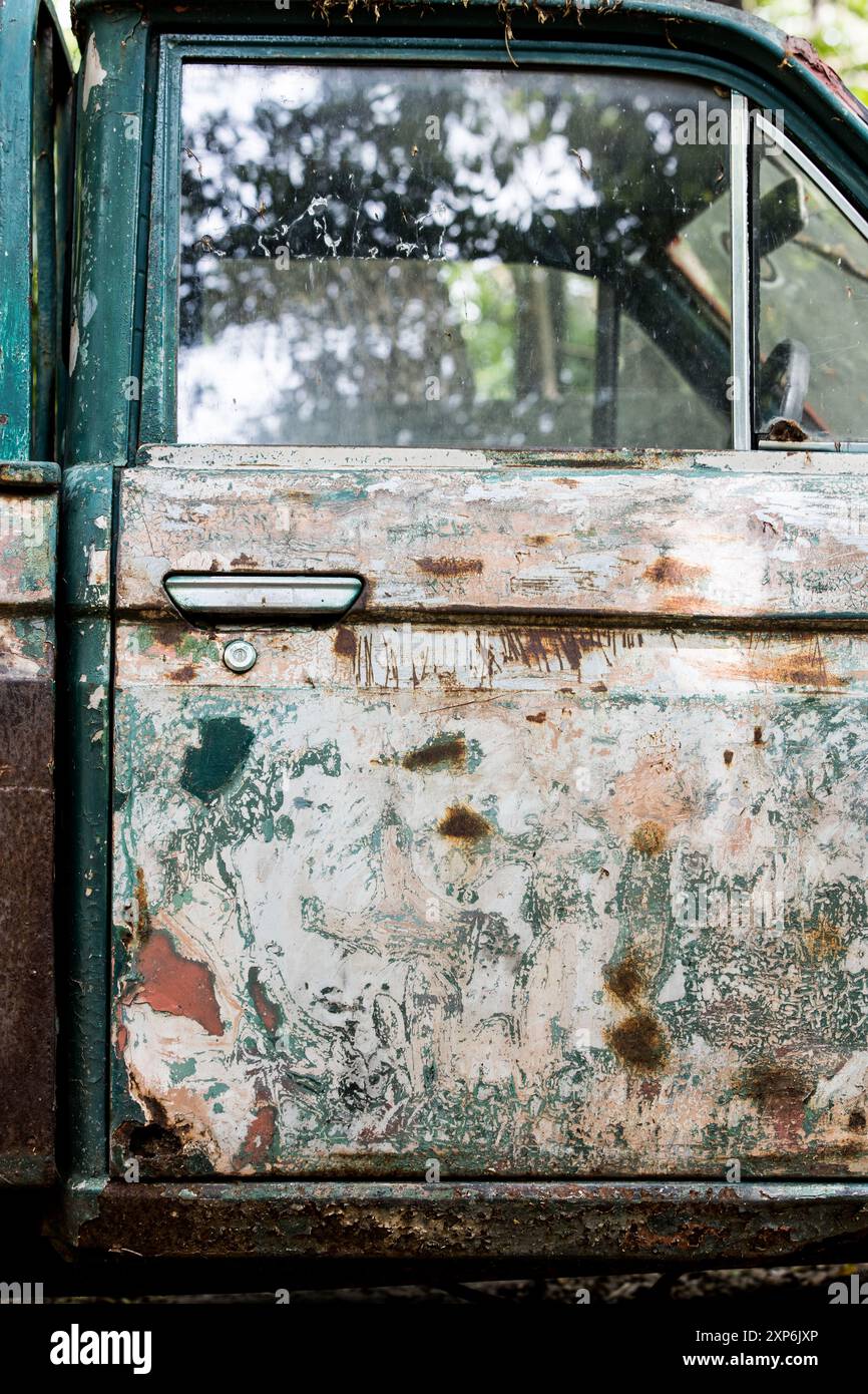 Side view of an old olive-green car, paint peeling, rough, and erosion ...