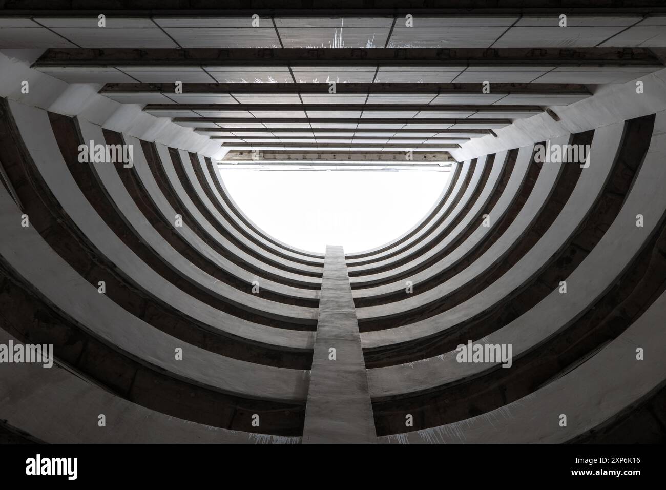 Bottom view of circular car parking garage against white clouds and ...