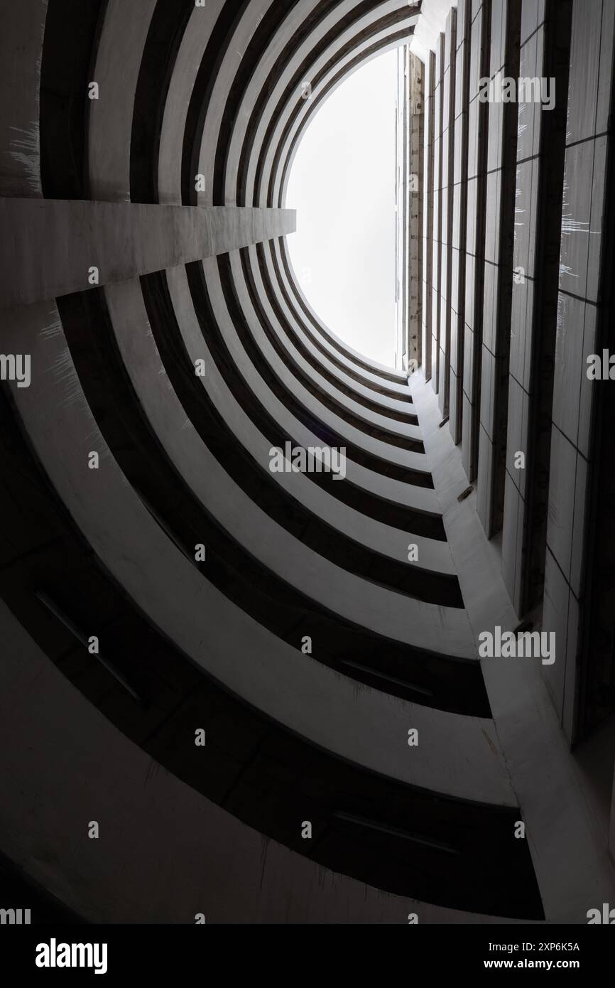 Bottom view of circular car parking garage against white clouds and ...