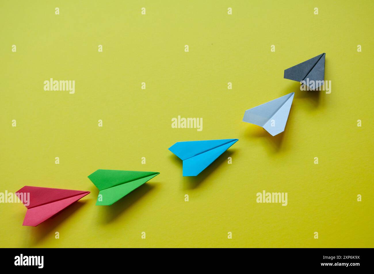 Black paper airplane leading the rest of the multicolored paper ...