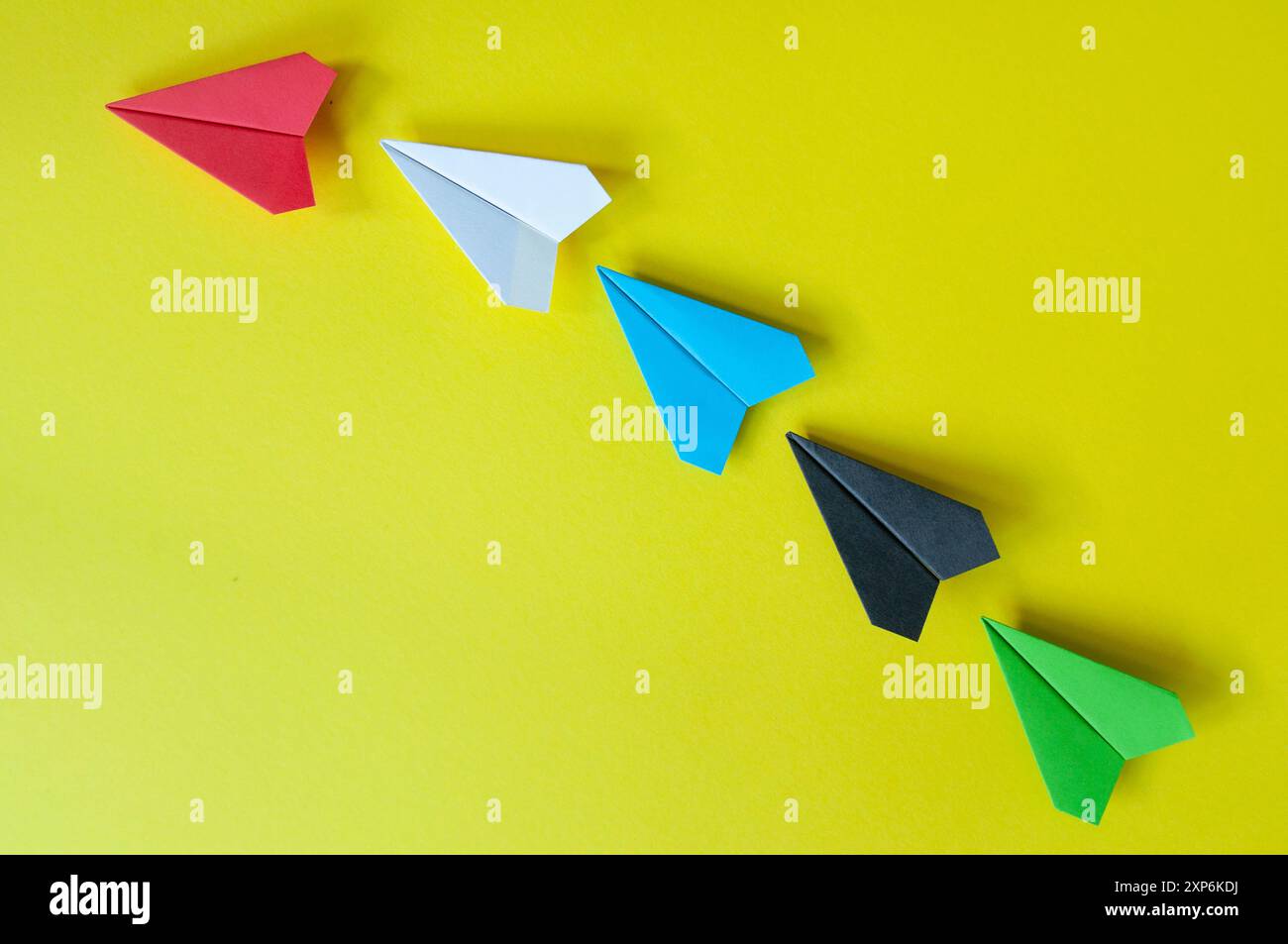 Red paper airplane leading the rest of the multicolored paper airplanes ...