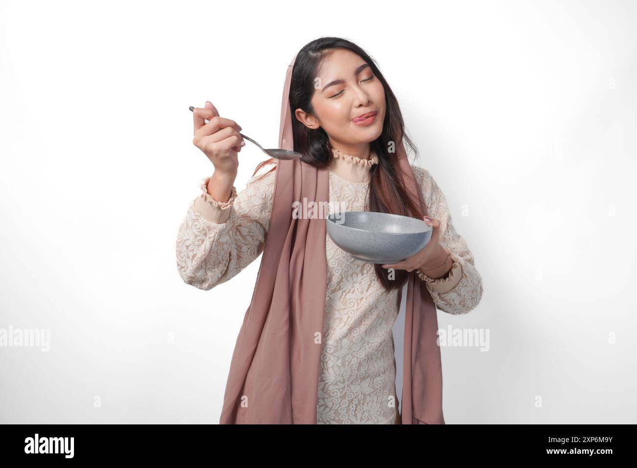 Portrait of a hungry Asian Muslim woman holding cutlery to eat or taste ...