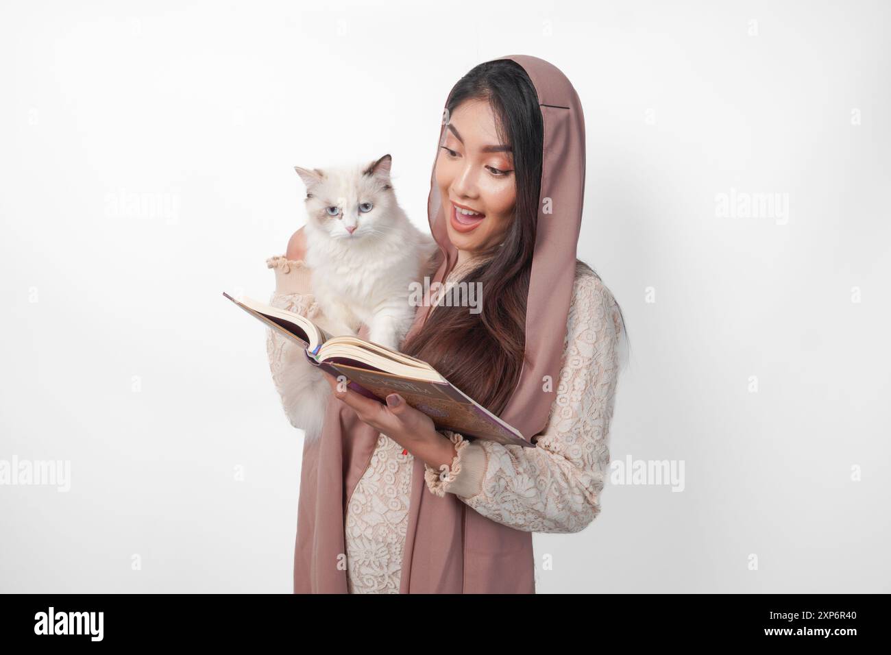 Attractive young Asian Muslim woman in veil hijab smiling while hugging ...