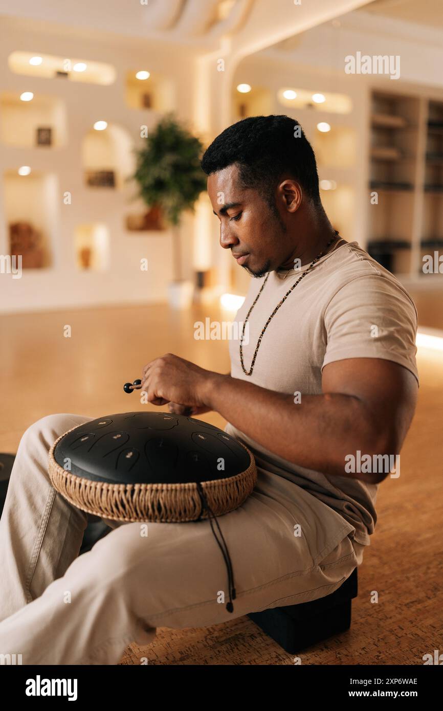 Vertical portrait of serene black male practicing native music ...