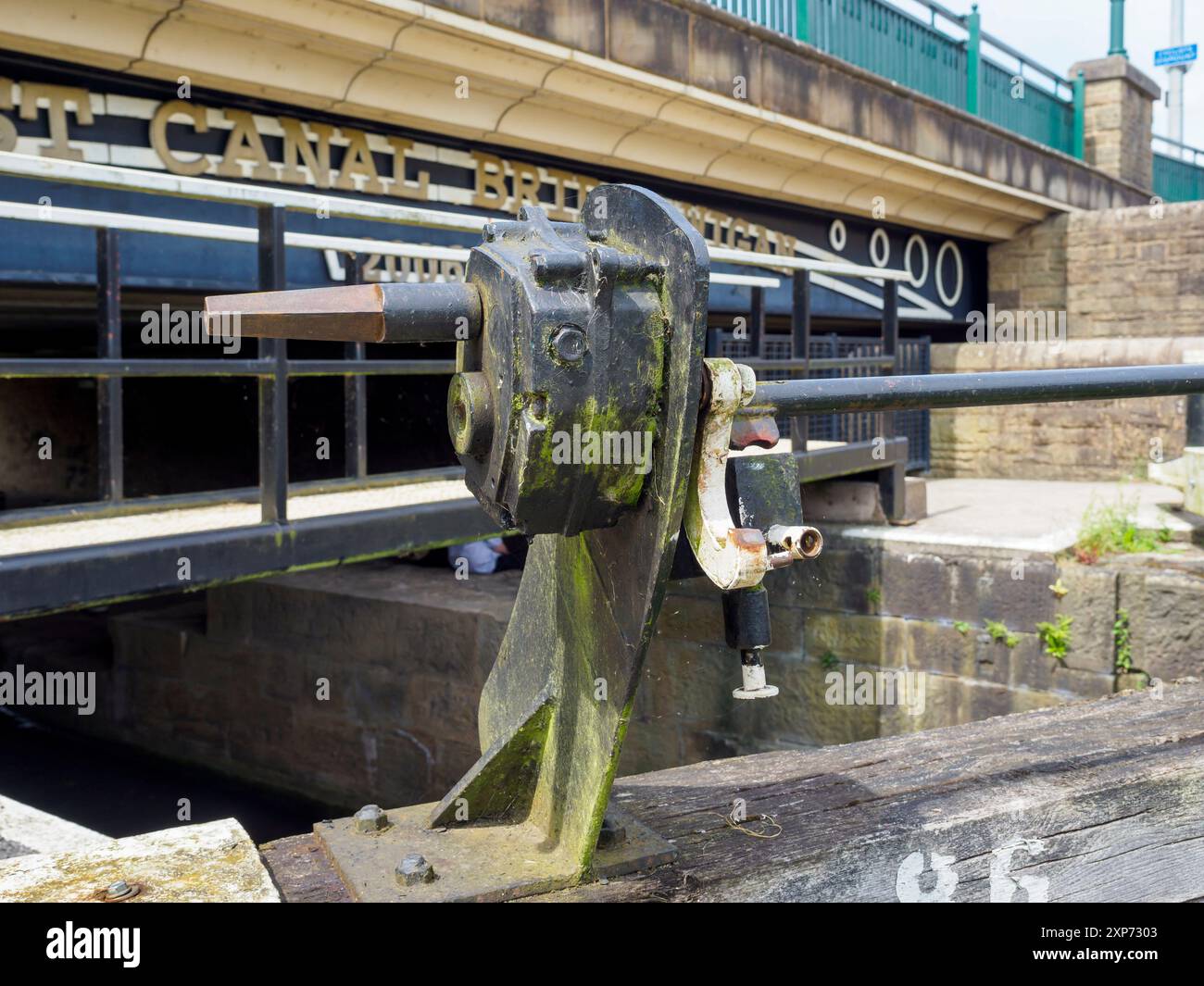 Rustic canal lock lever near a historical bridge with moss and ...