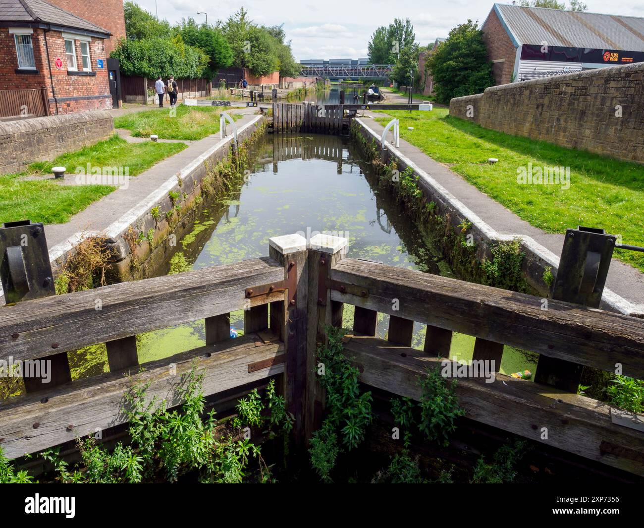 Historic canal lock gate surrounded by green banks with distant ...