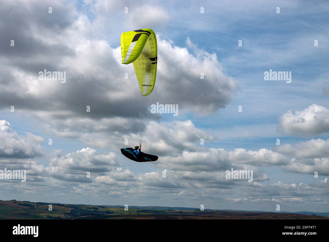 Yellow hang glider flying along Stanage Edge, the Peak District ...