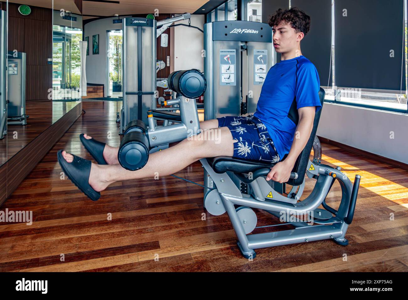 A young adult male using a weights machine in a gym to exercise and ...