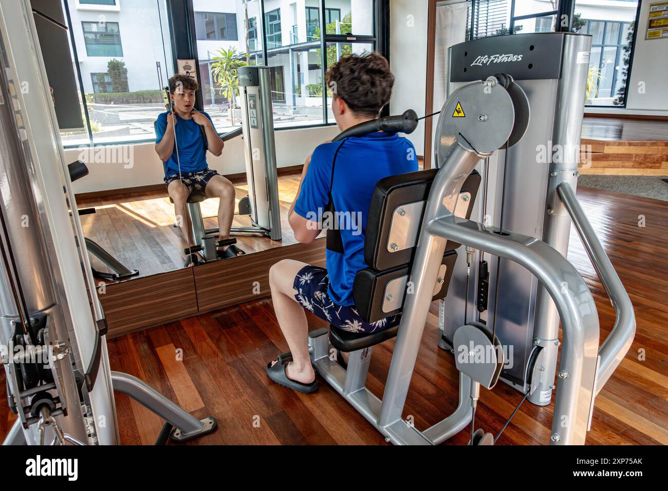A young adult male using a weights machine in a gym to exercise and ...