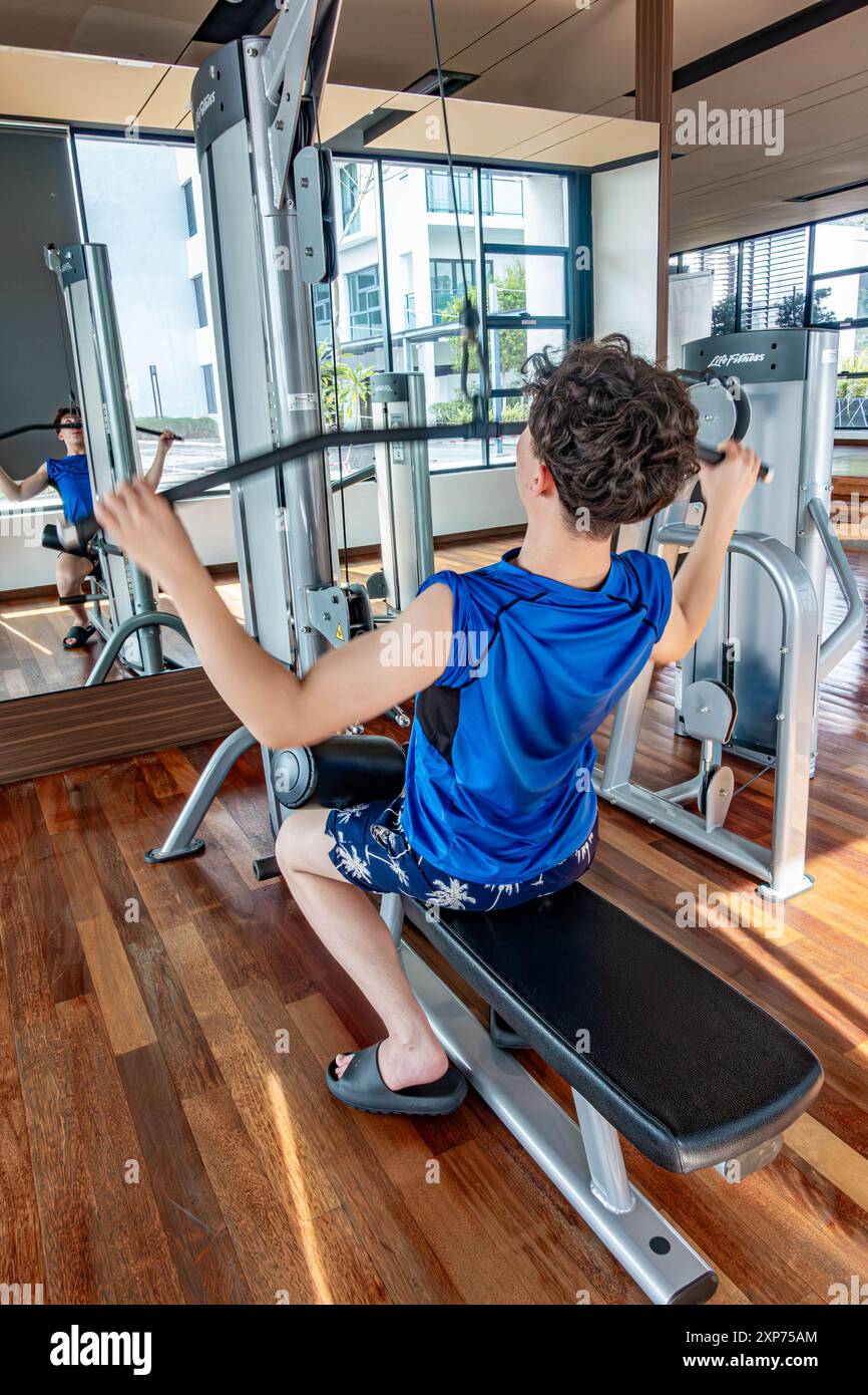 A young adult male using a weights machine in a gym to exercise and ...