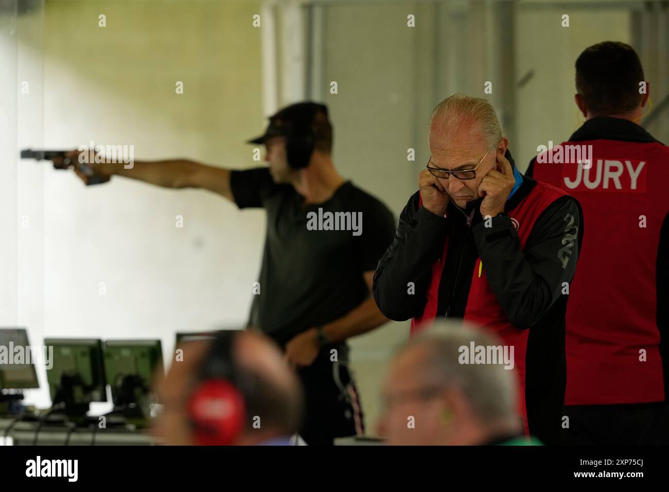 A jury member closes his ears during the 25m rapid fire pistol men's ...
