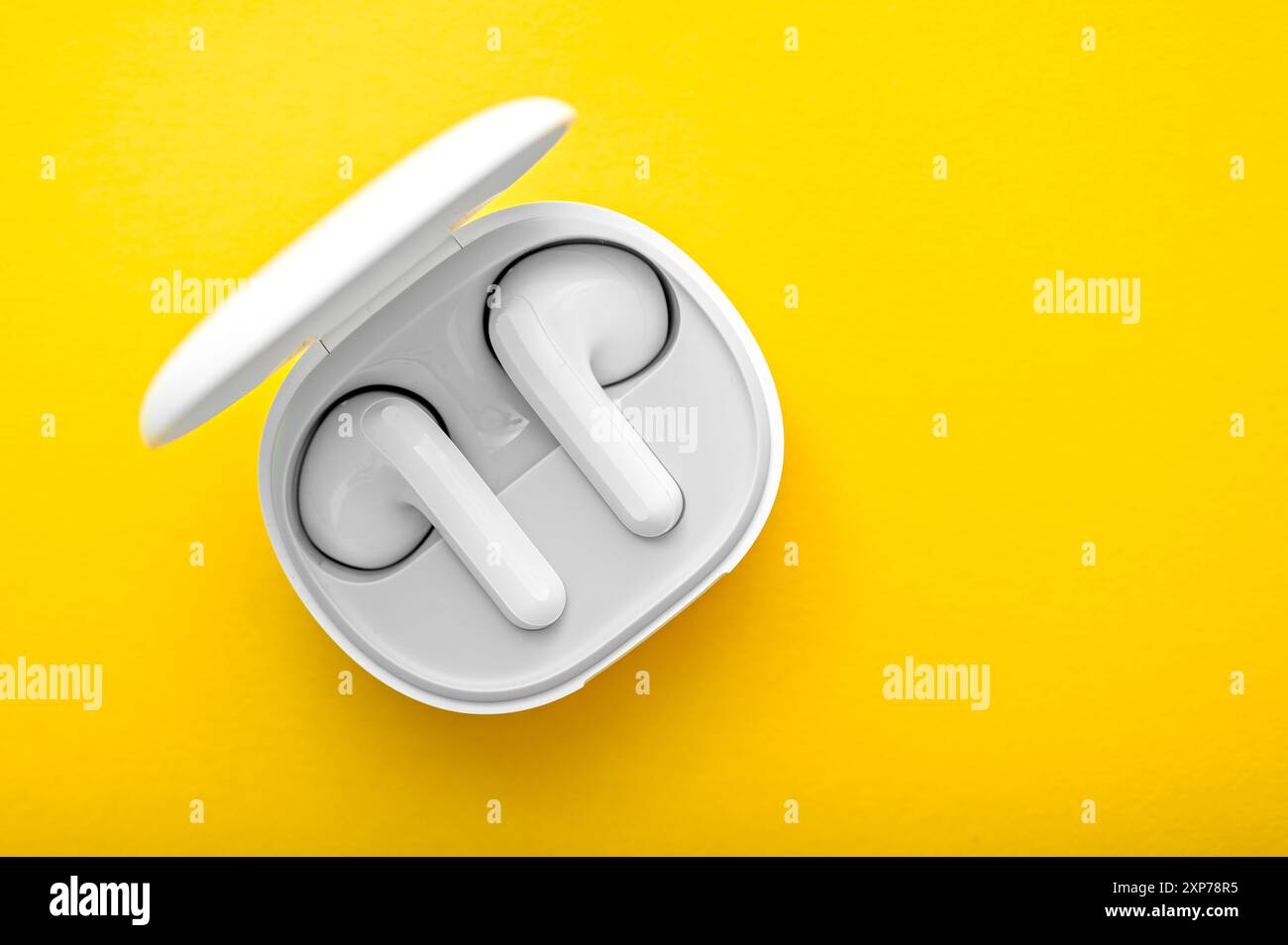 Top view of opened case with white wireless headphones on bright yellow ...