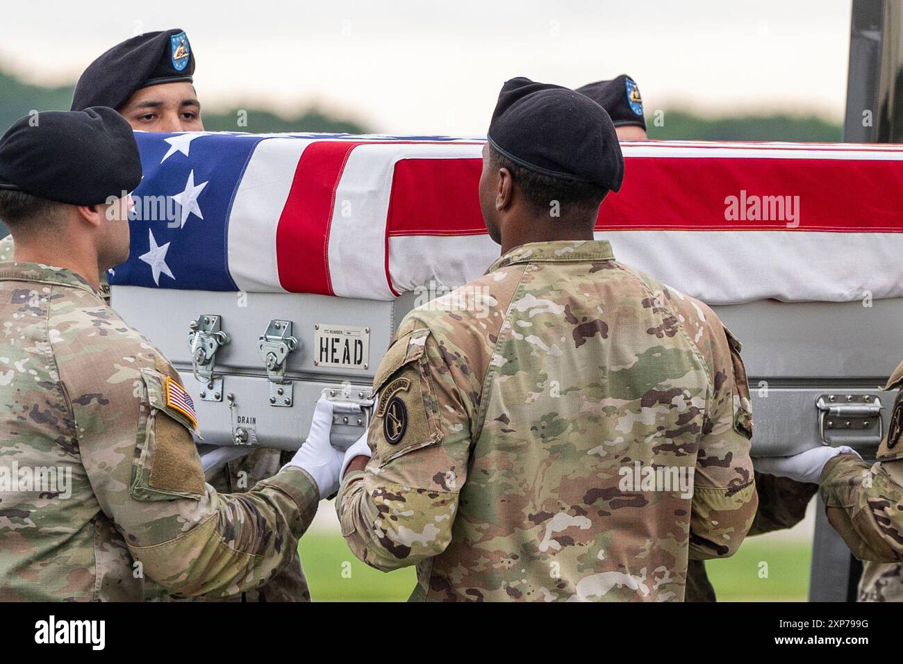 An Army carry team places the flag-draped transfer case containing the ...