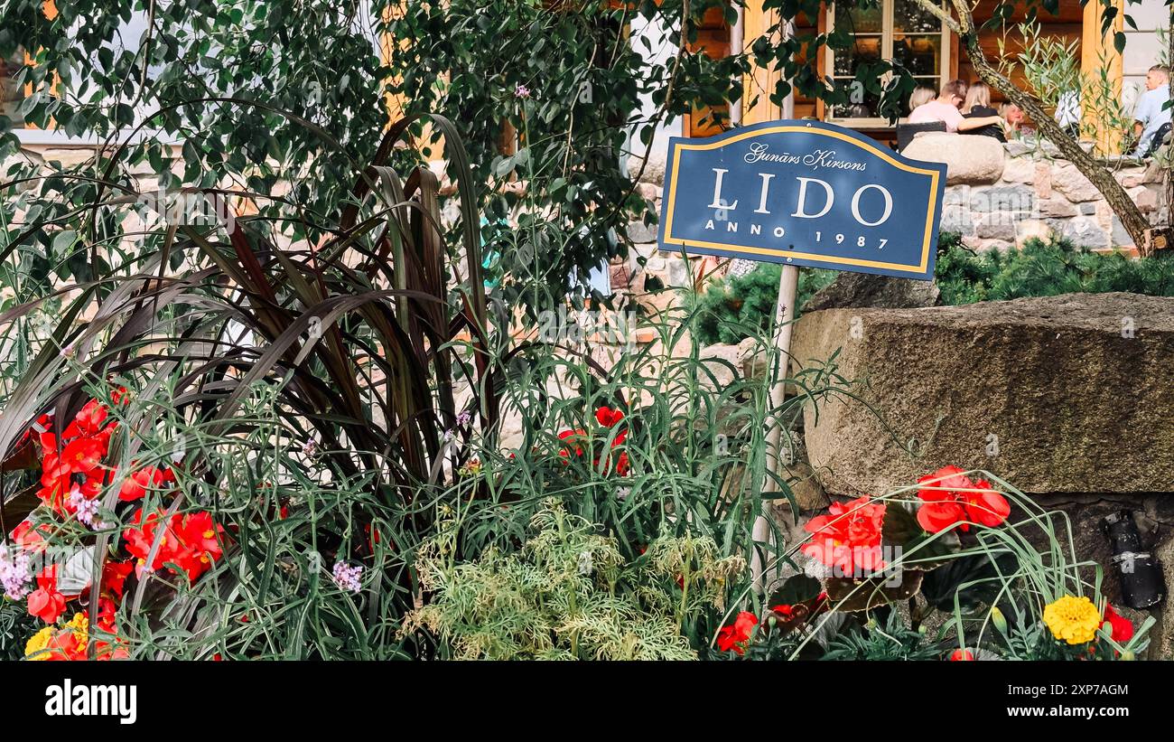 Riga, Latvia - 14 07 2024: In the garden, flowers blooming, sign says ...