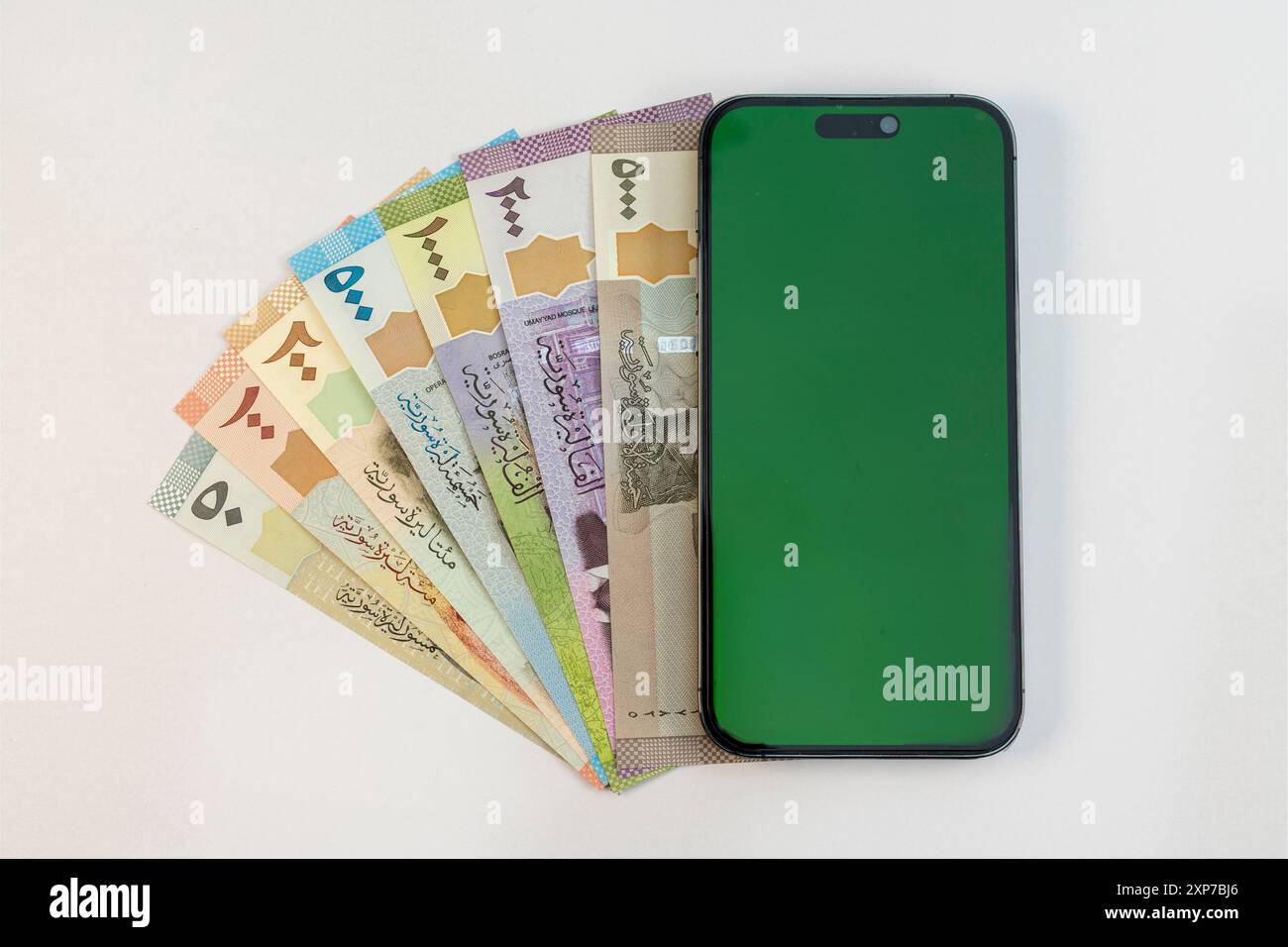 Syrian currency notes and Smartphone with green blank screen isolated ...