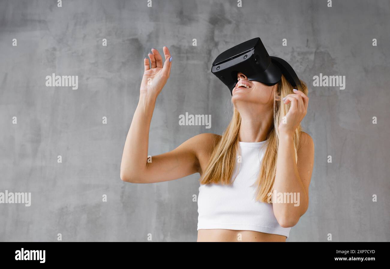 Female figure engages with virtual reality technology in over grey wall ...