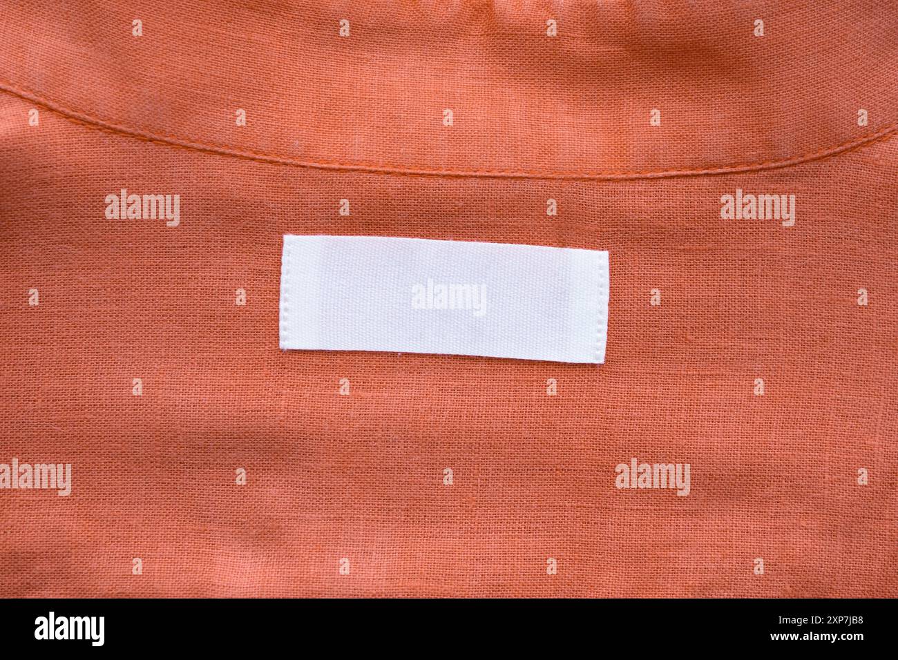 White blank clothing tag label on linen shirt fabric texture background ...
